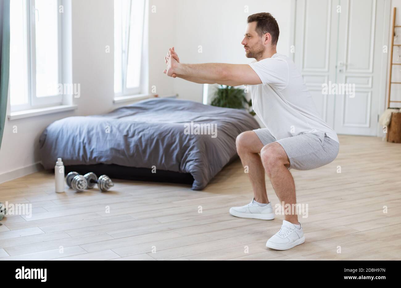 Sporty Guy Doing Two-Legged Squat Exercise At Home Stock Photo - Alamy