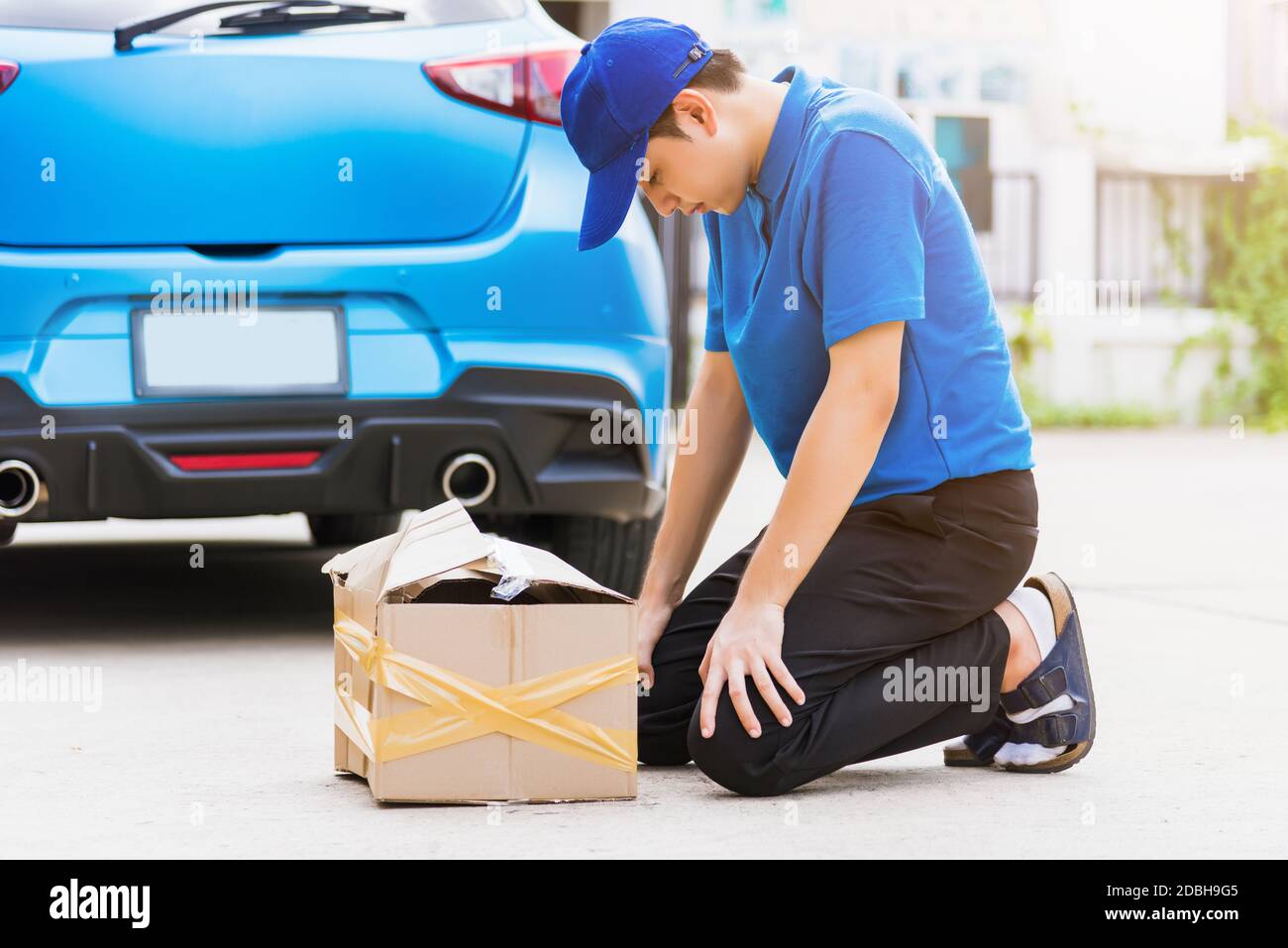 Asian young delivery man in blue uniform he emotional falling courier ...