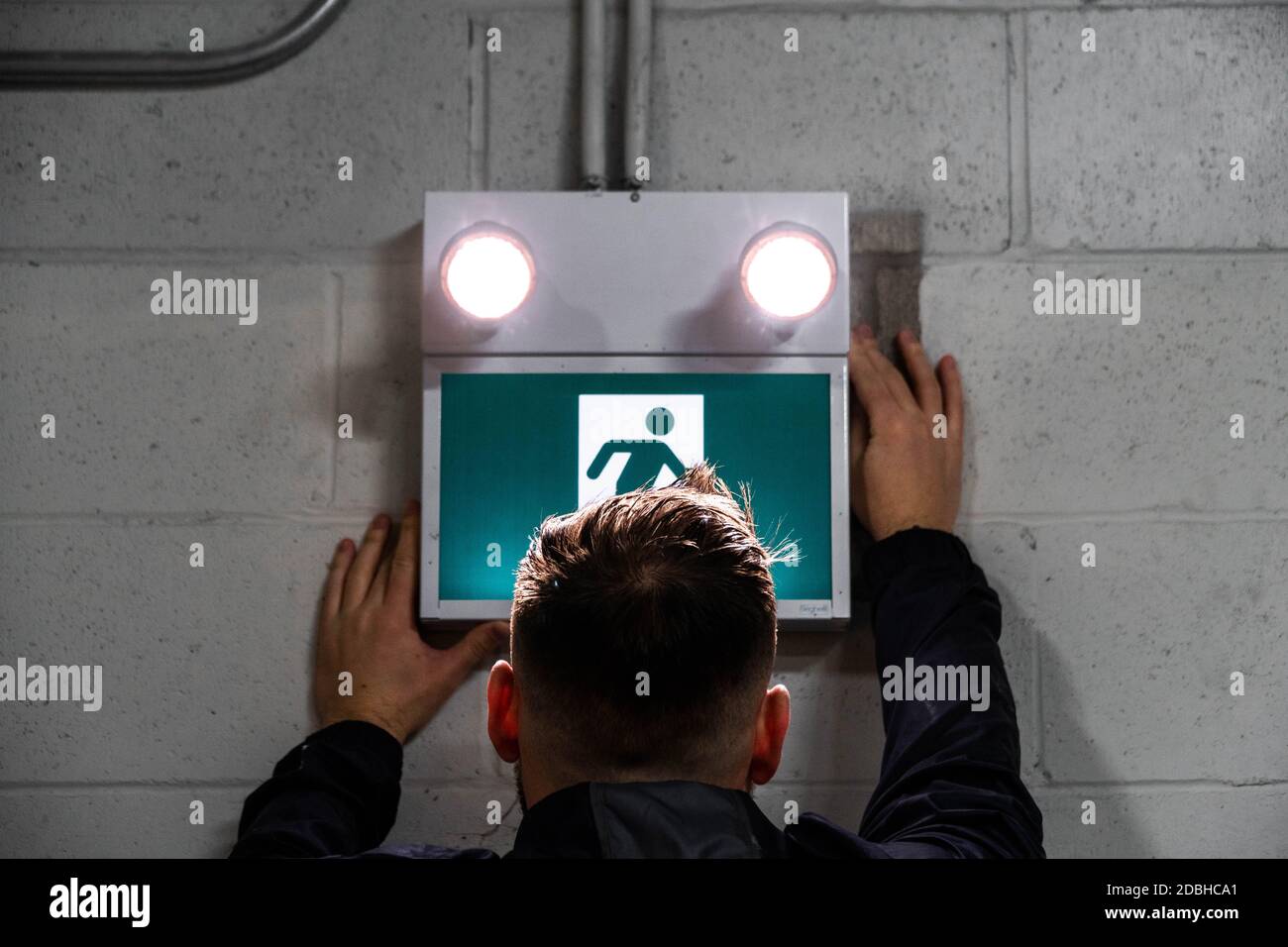 Unrecognizable technician checks emergency light on exit sign fire ...