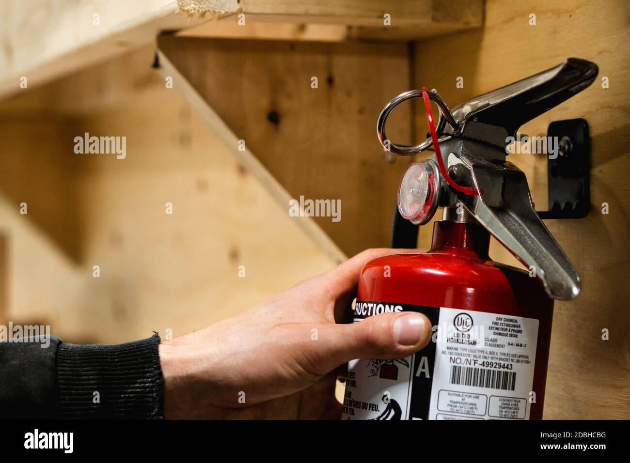 Technician hand off screen replaces fire extinguisher on hook wooden ...