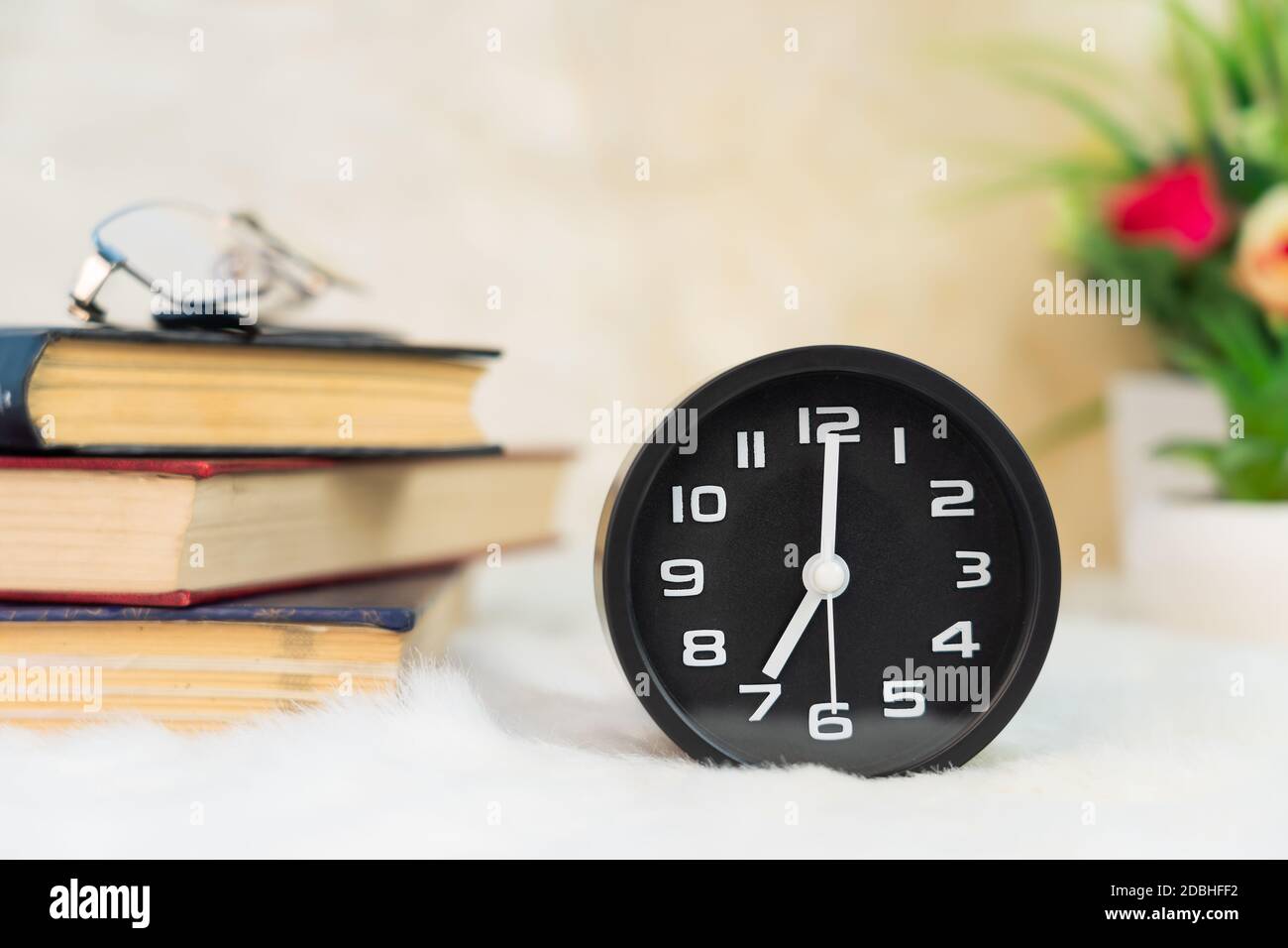 Close up Black alarm clock with book stacked on table Stock Photo - Alamy