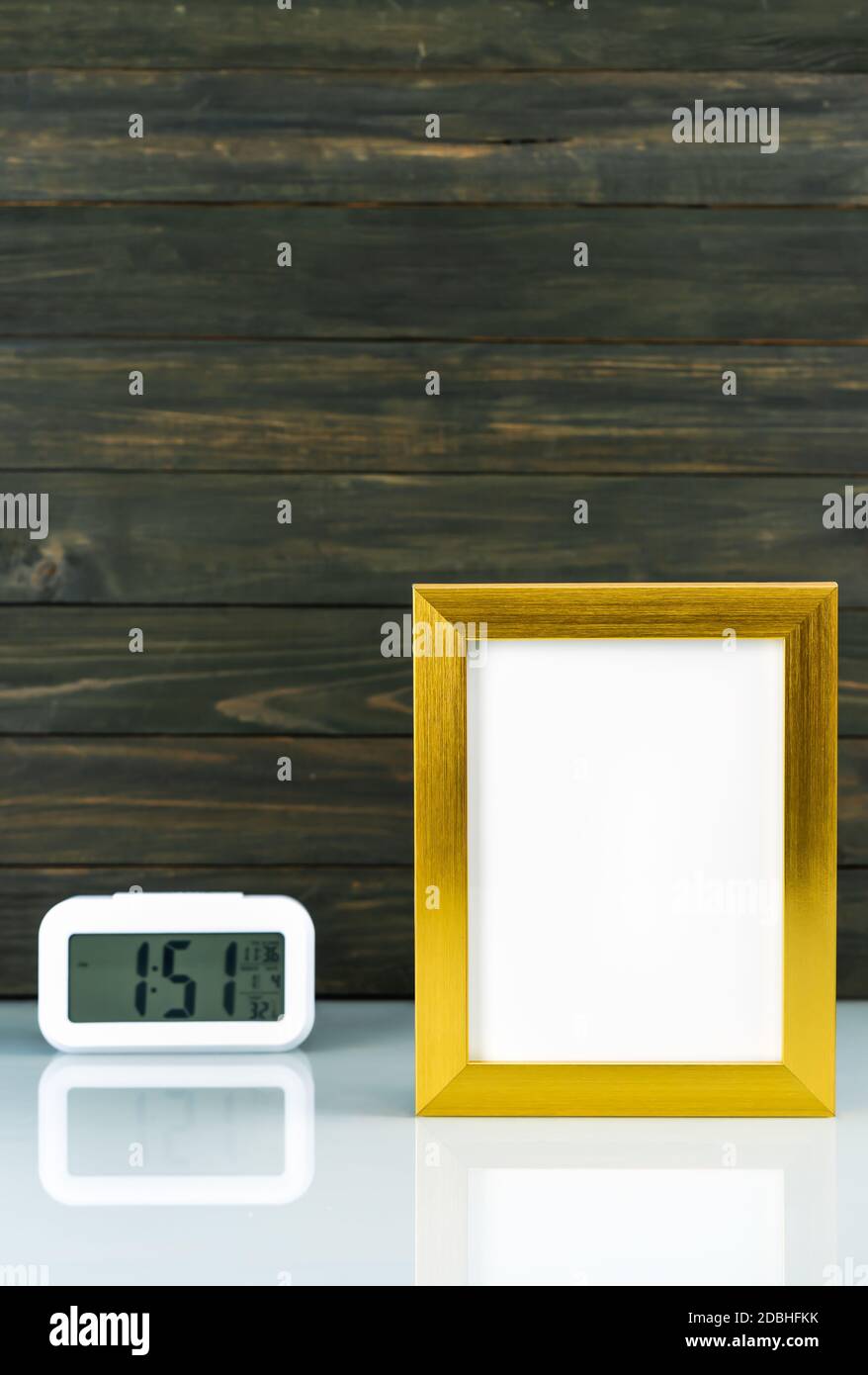 Mock up with blank golden frame and digital alarm clock on table with ...
