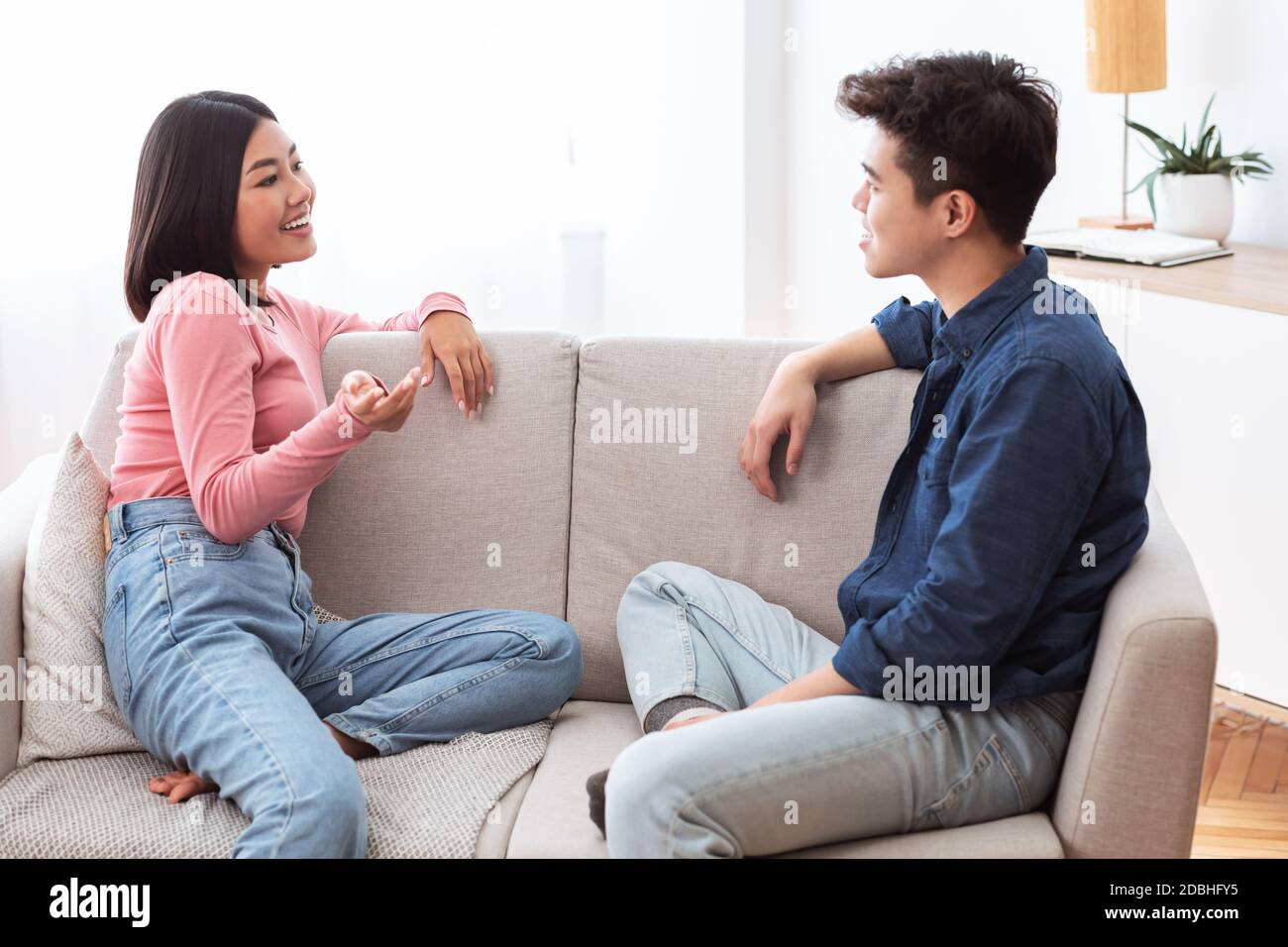 Asian Couple Talking Enjoying Conversation Sitting On Couch At Home ...