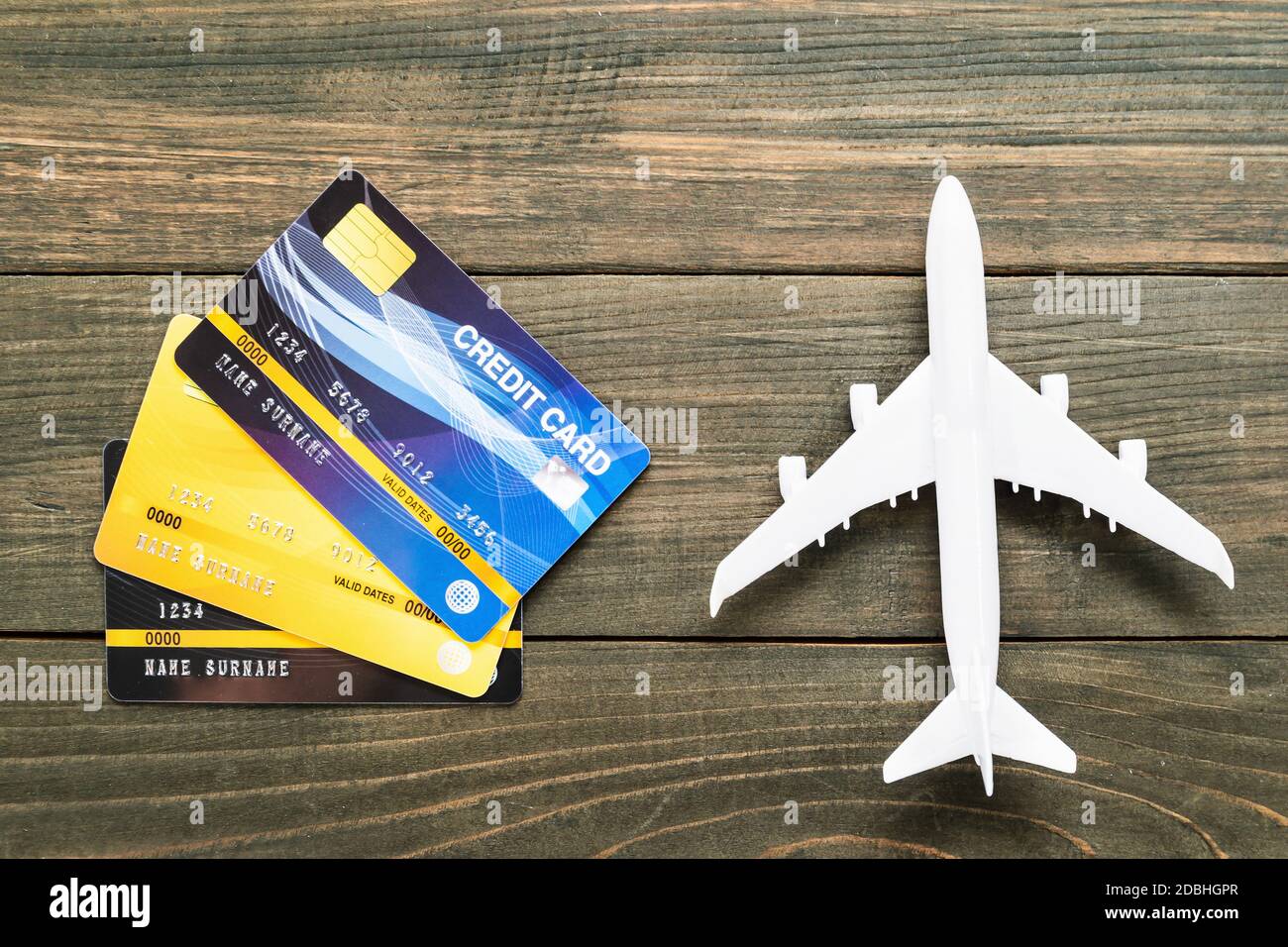 Credit card and airplane model on brown wooden desk background ...