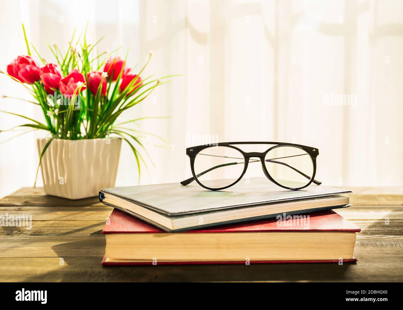 Eye glasses are placed on books on wooden table beside the window Stock ...