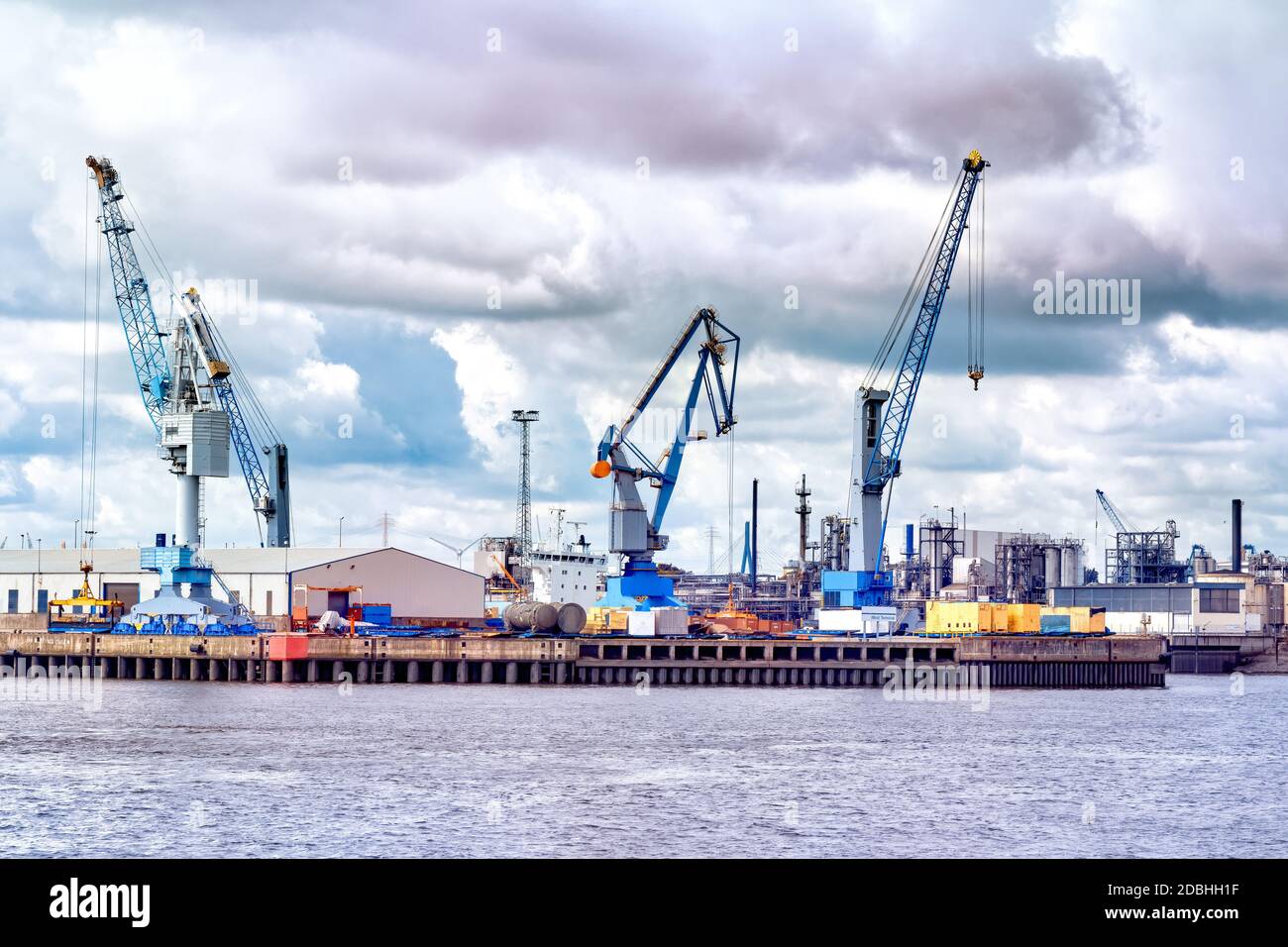 Containers, docks and cranes in the port of hamburg under stormy sky ...
