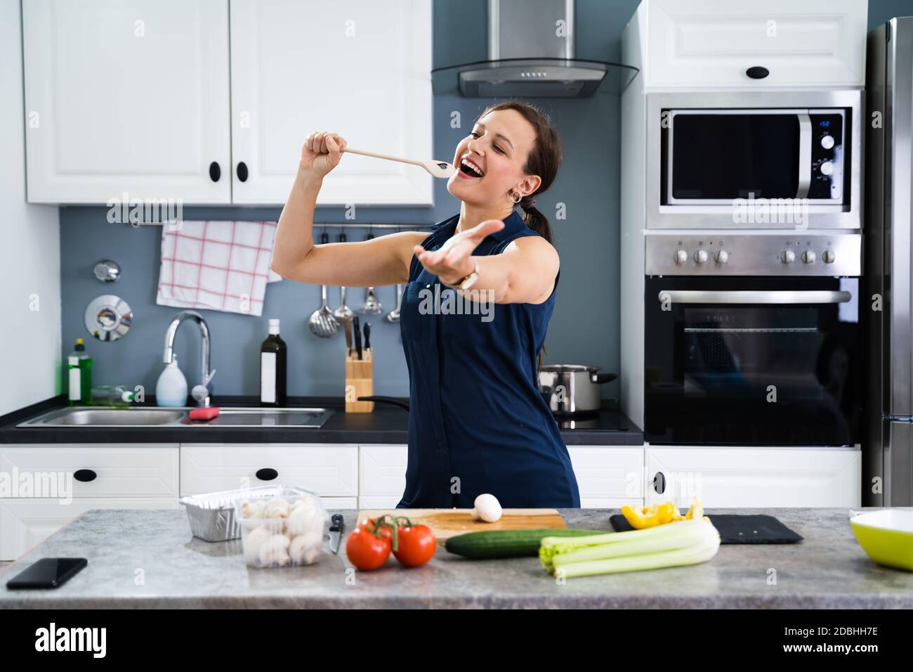 Woman Dancing And Singing While Cooking In Kitchen Stock Photo - Alamy