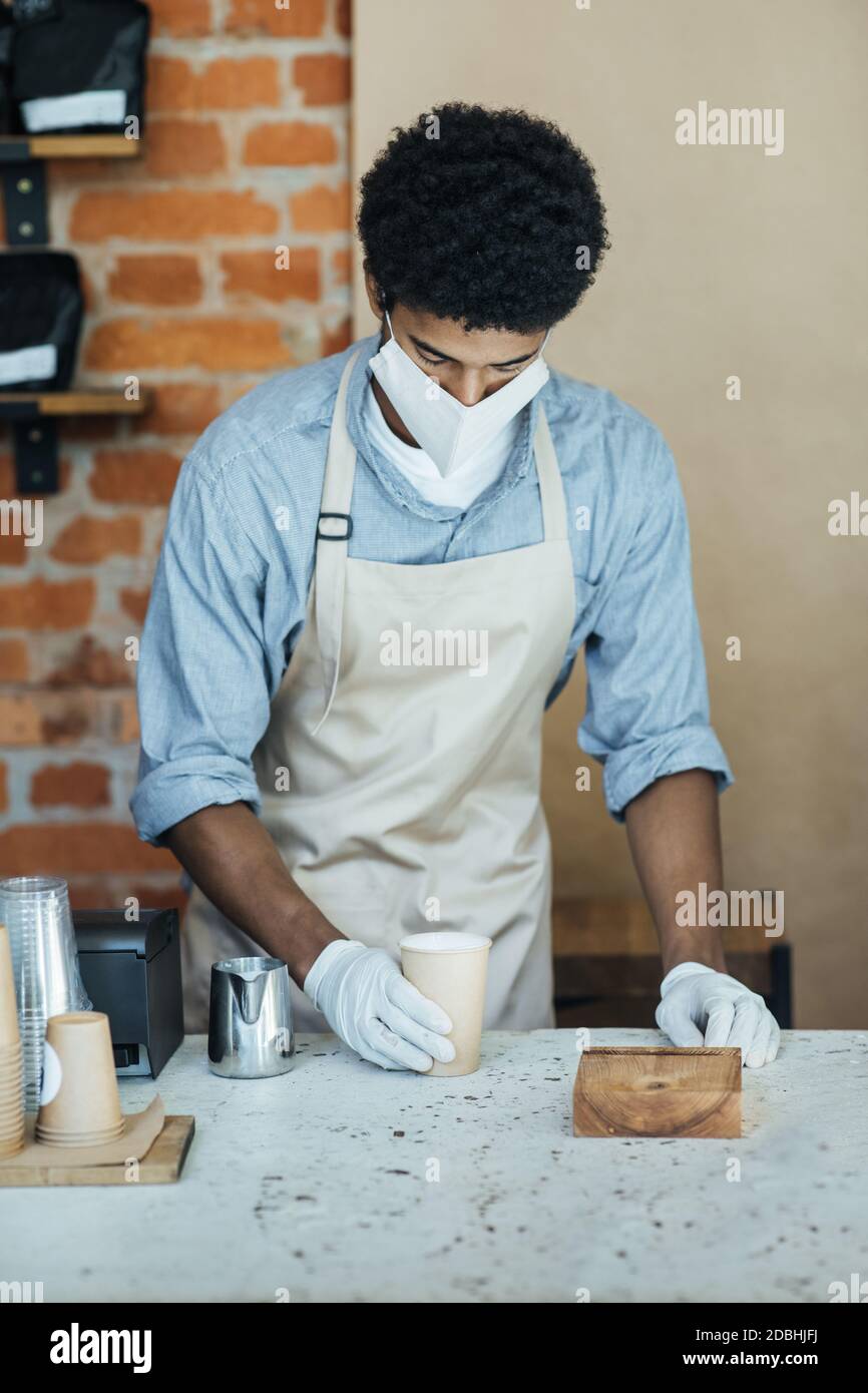 Barista in medical gloves makes cappuccino coffee in coffee shop after ...