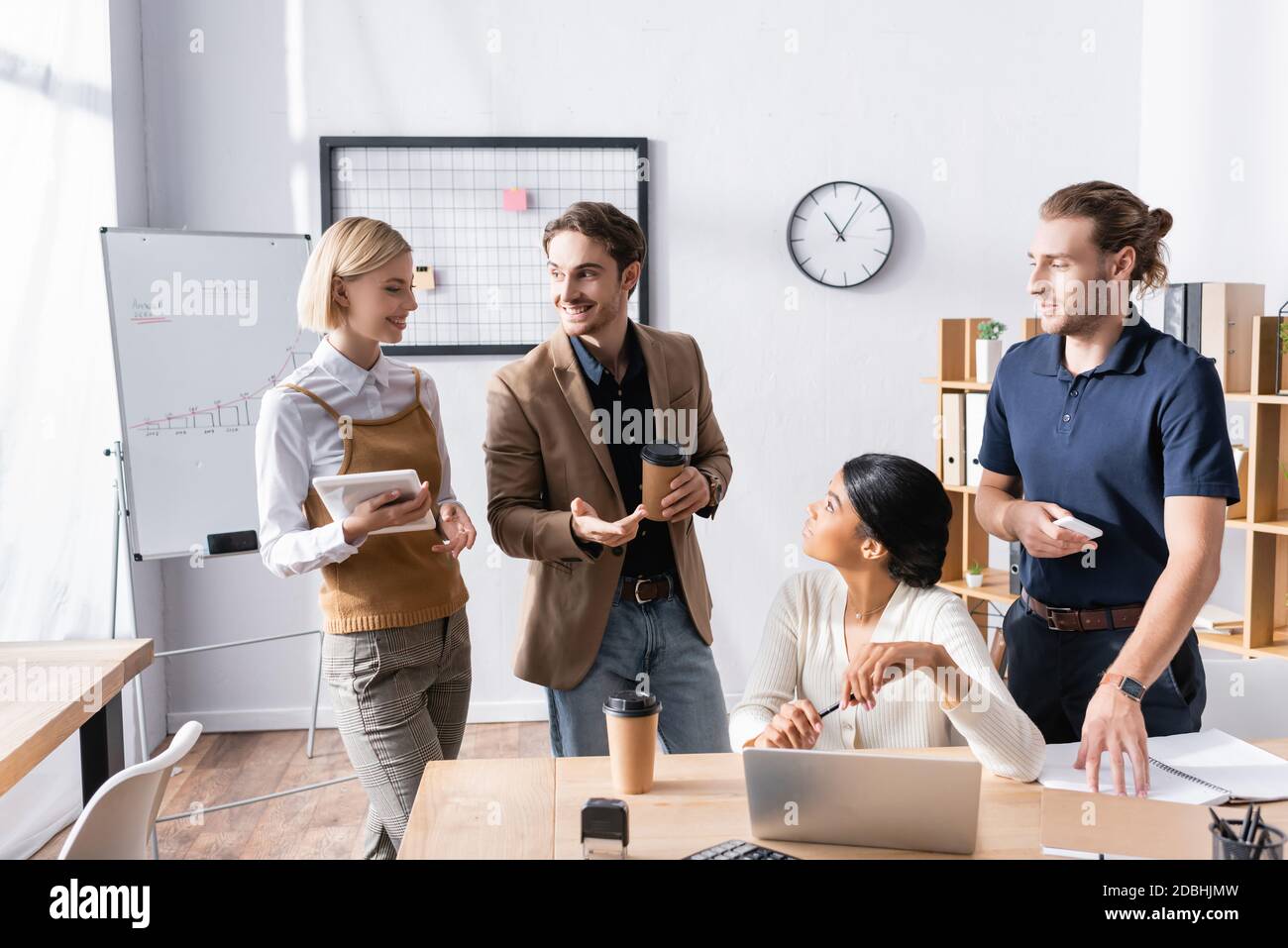 Skeptical multicultural office workers looking at smiling colleagues ...