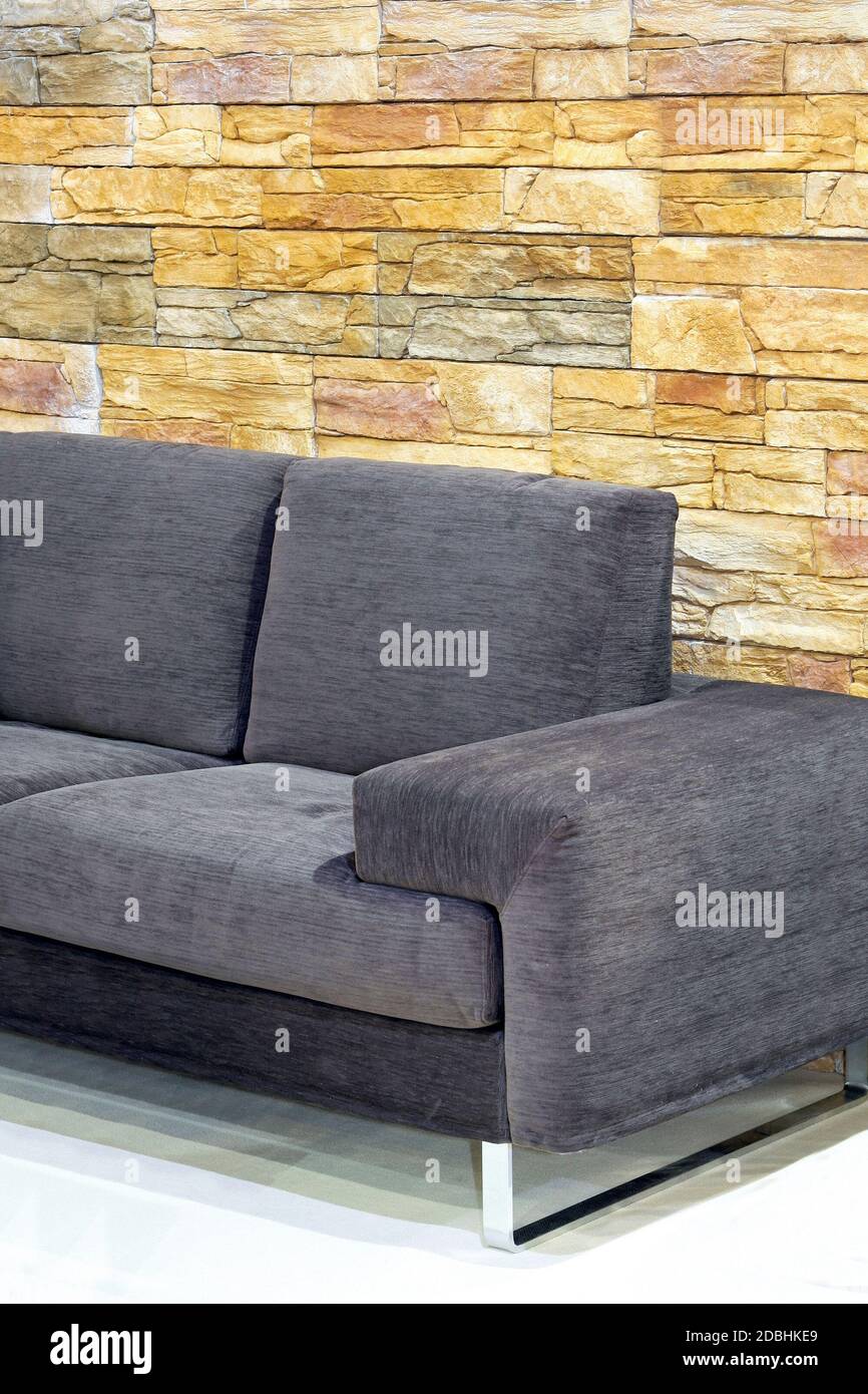 Grey sofa with wall made from sold stones Stock Photo - Alamy