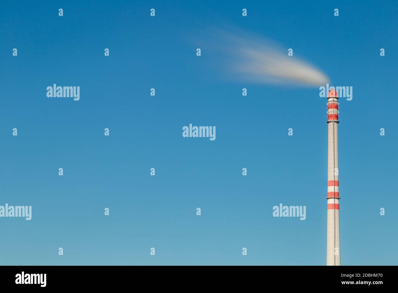 Industrial smokestack in wind. Dirty smoke from red and white factory ...