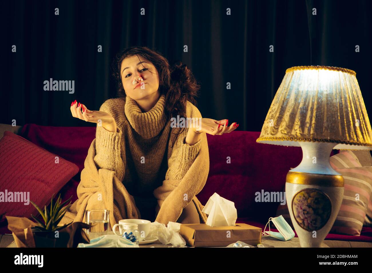 Rainy nose. Young woman wrapped in a plaid looks sick, ill, sneezing ...