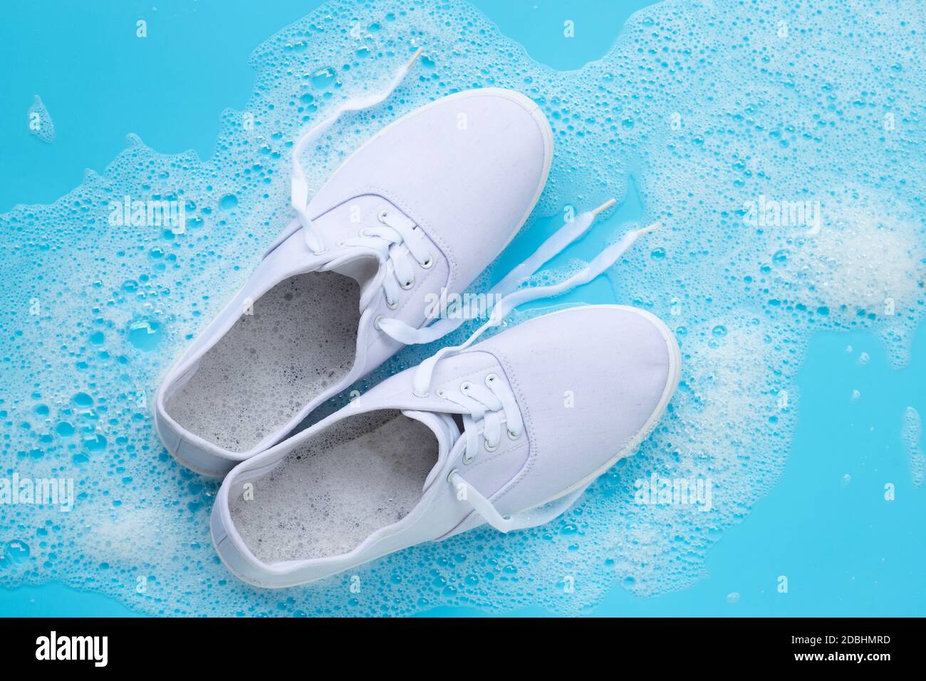Sneakers with foam of powder detergent water dissolution on blue ...