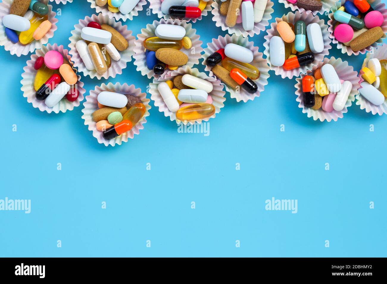 Colorful tablets with capsules and pills in cupcake wrappers on blue ...