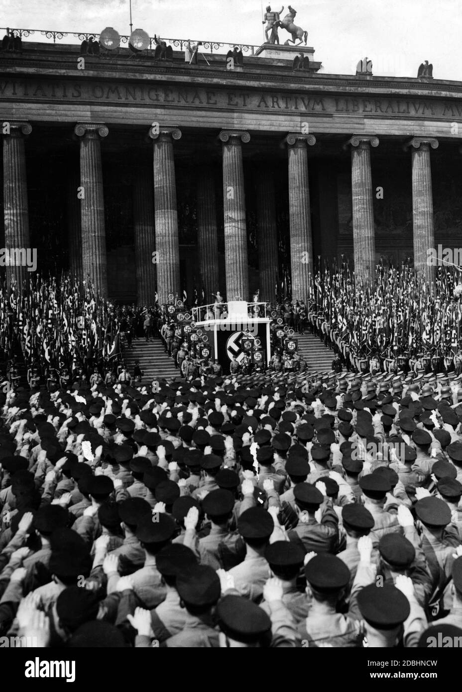 Adolf Hitler on the lectern performs the Nazi salute, party members of ...