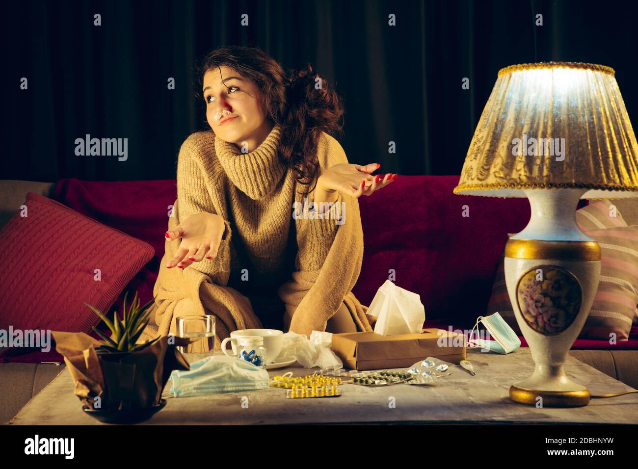 Rainy nose. Young woman wrapped in a plaid looks sick, ill, sneezing ...