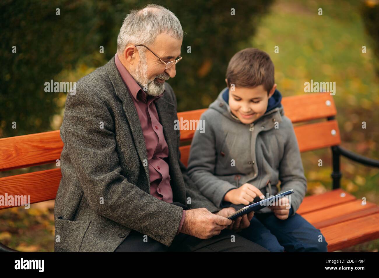 Grandpa and his grandson spend time together in the park. They are ...