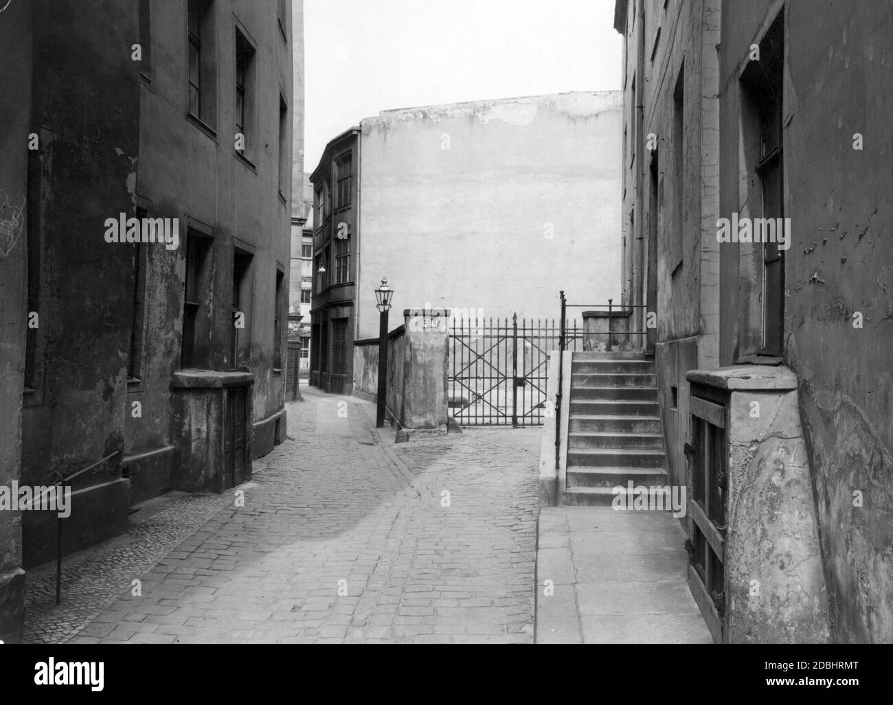 The picture from 1934 shows a narrow alleyway with simple houses in ...