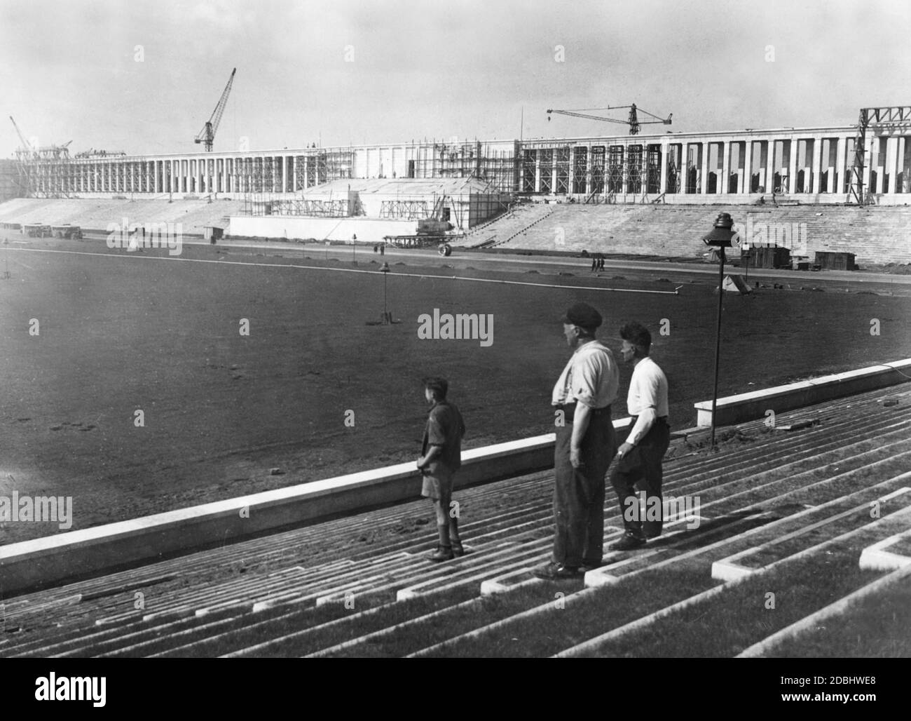 Three men look at the newly erected grandstands on the Zeppelin Field ...