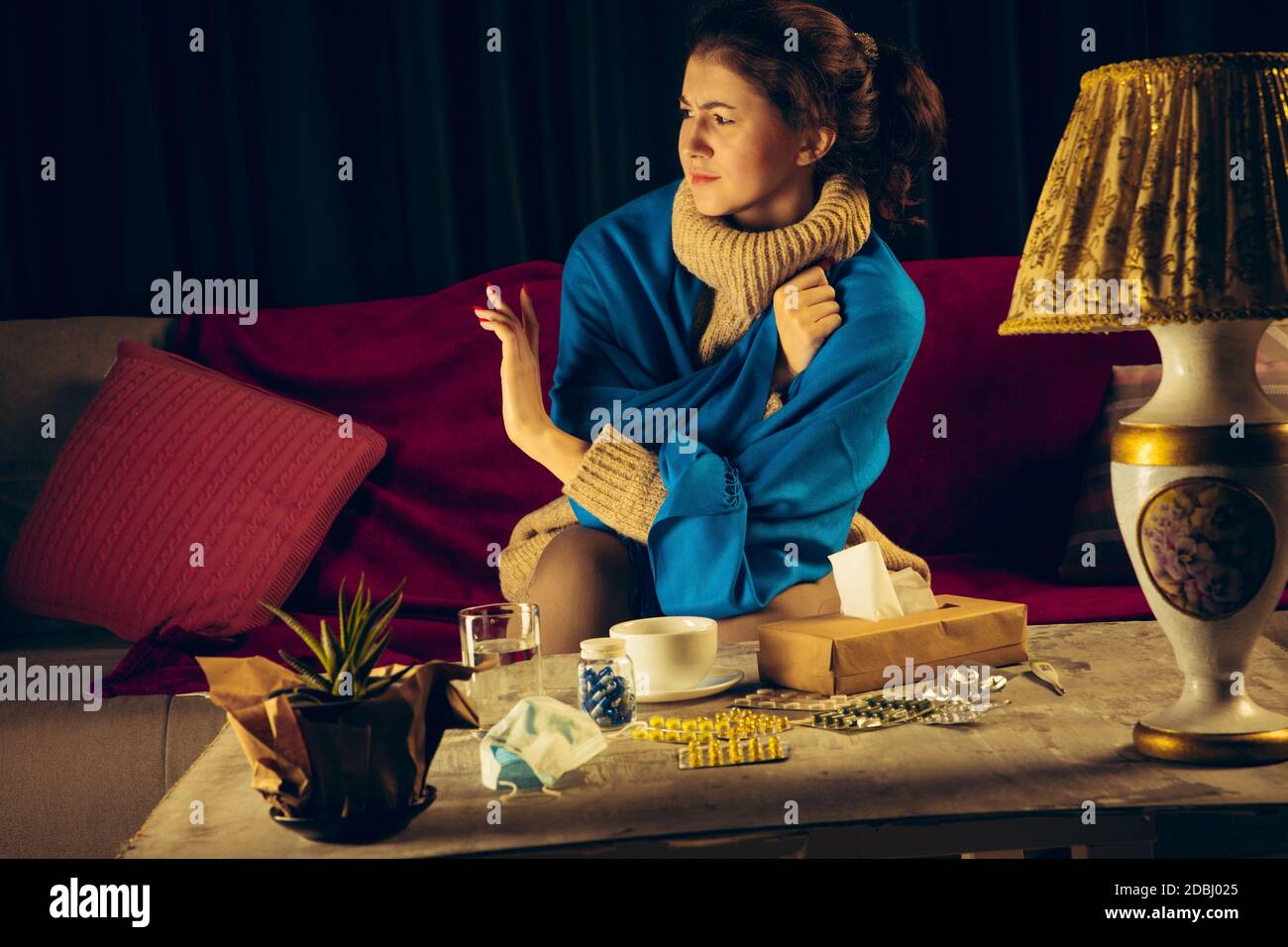 Scared. Young woman wrapped in a plaid looks sick, ill, sneezing and ...