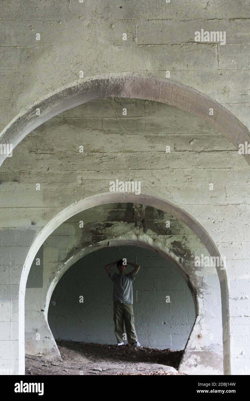 A teen boy standing in the background behind several arches Stock Photo ...