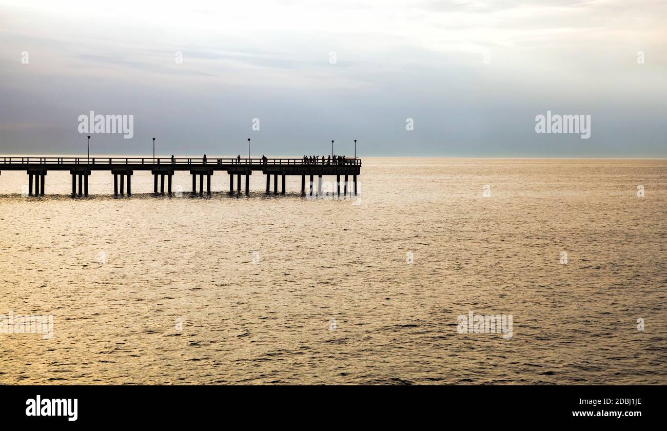 long pier in the sea with waves on the water during sunset or sunrise, seascape on the Baltic ...