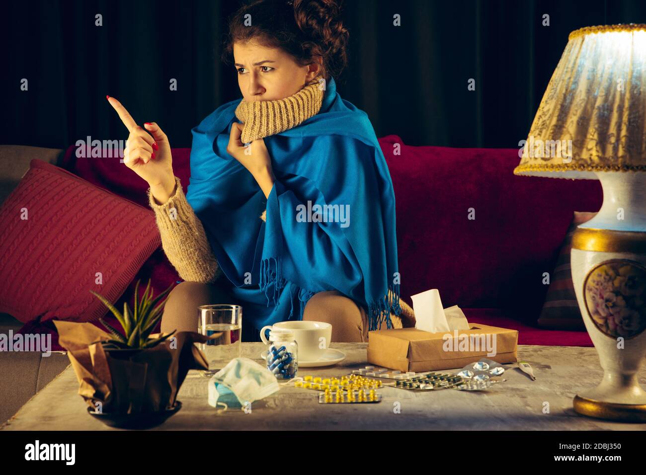 Angry. Young woman wrapped in a plaid looks sick, ill, sneezing and ...