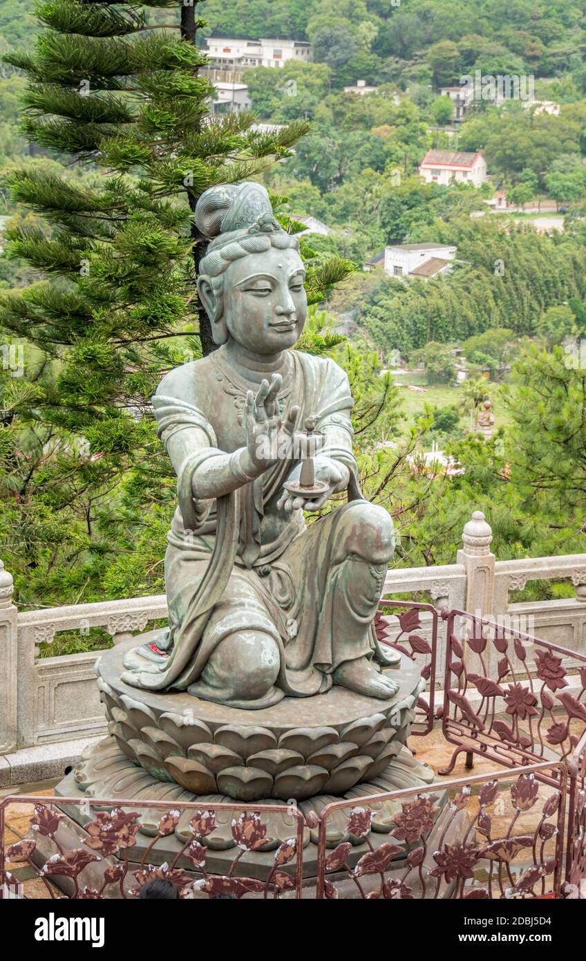 Buddhist Deva statue offering a lamp to the Tian Tan Big Buddha statue ...