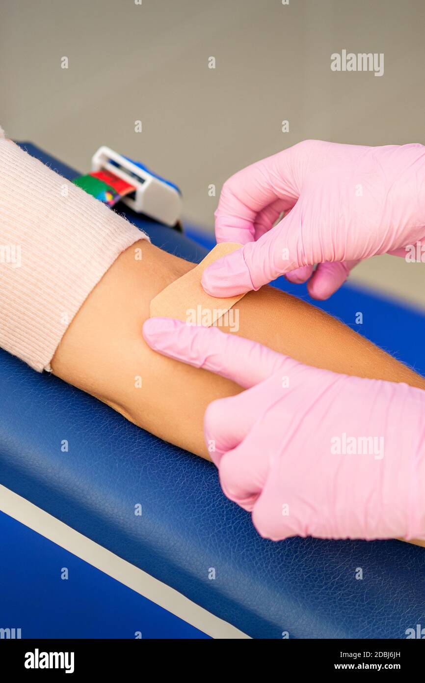 Close up of nurse hand applying adhesive plaster on arm of patient ...