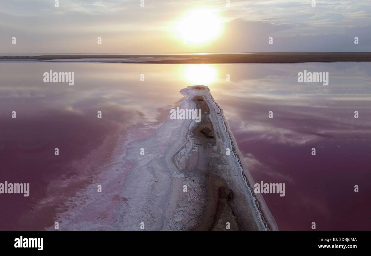 Bright sunset on a pink lake, orange flare on the pink water of the ...