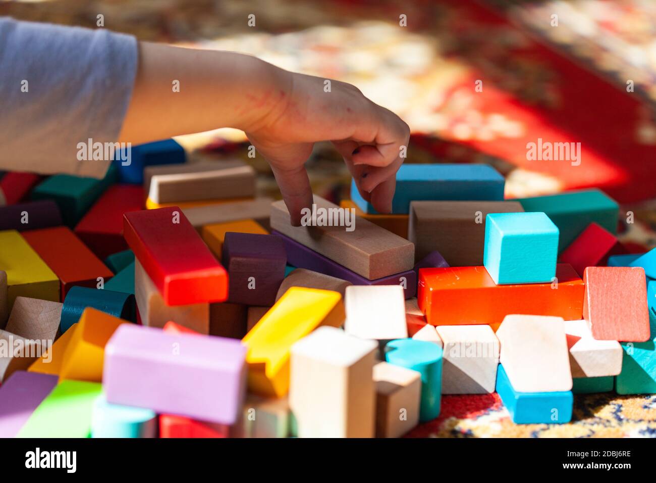 Playing colorful wooden cubes on carpet, hands Stock Photo - Alamy
