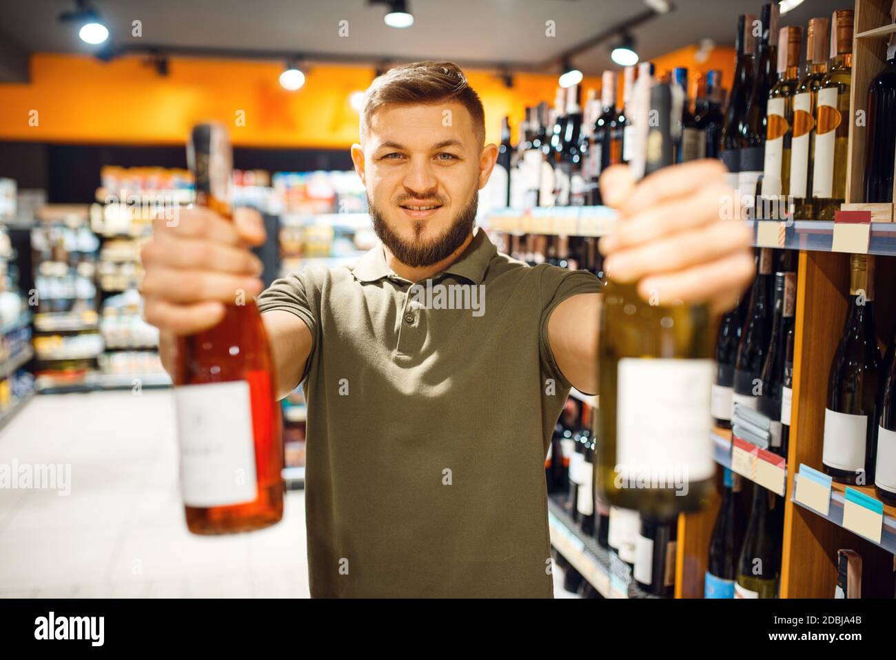 Man with two bottles of alcohol in grocery store. Male person buying ...
