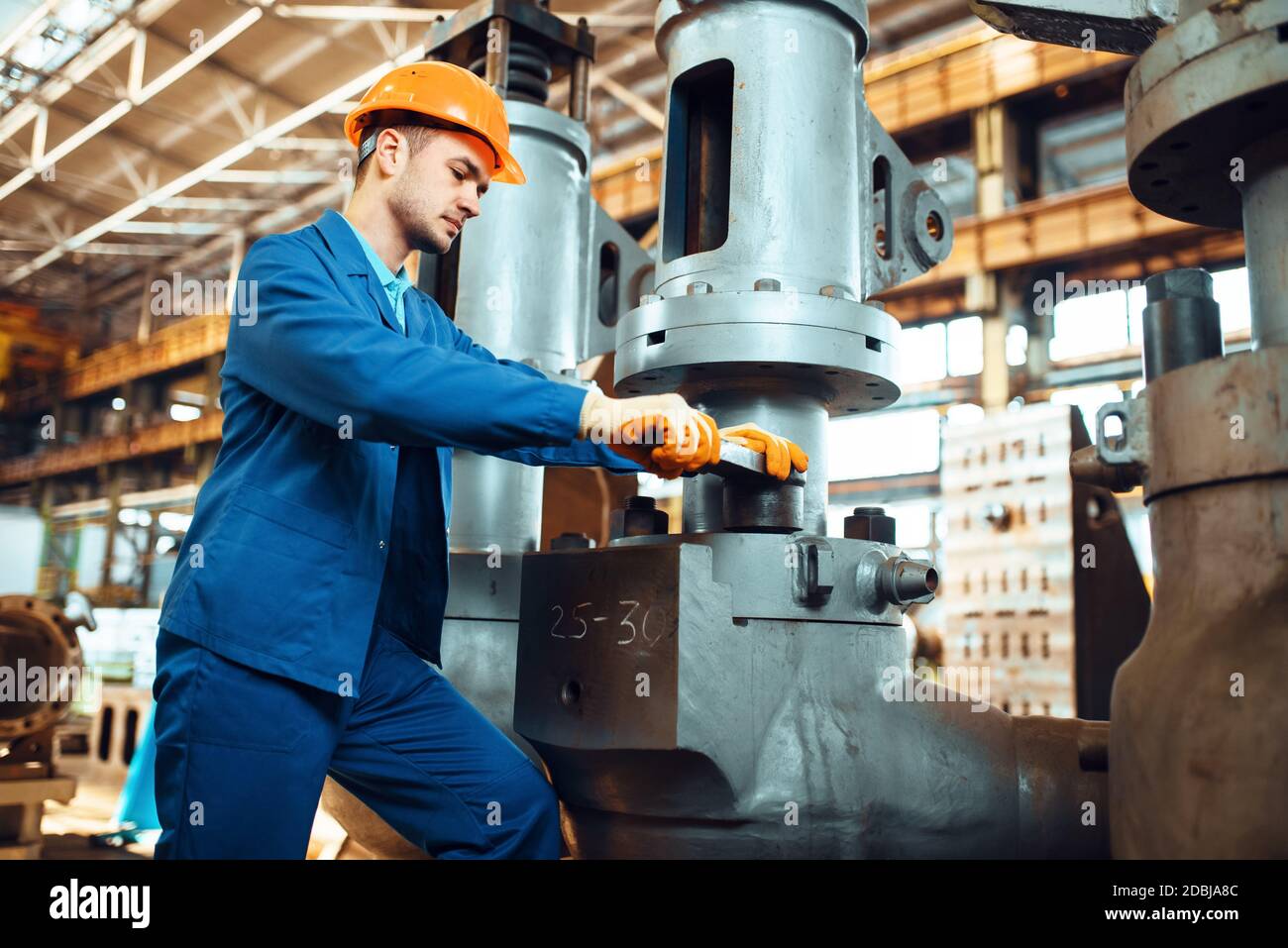 Engineer in uniform and helmet works on factory. Industrial production ...