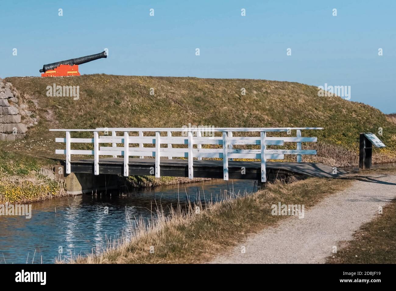 A wooden bridge over a small river. A gun on a hill. Open-air museum ...