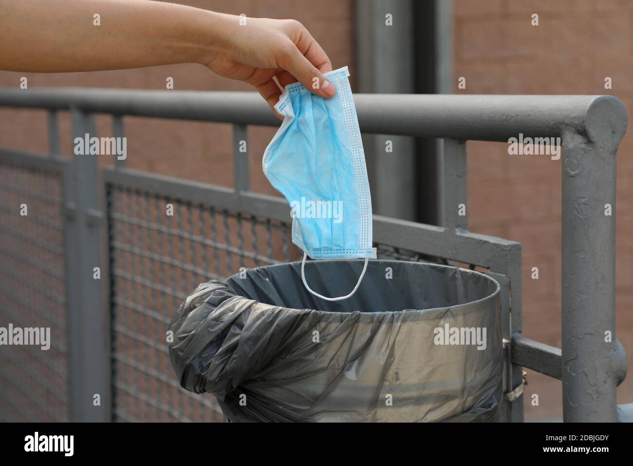 Throw surgical mask in public garbage can in city street. Hygienic mask ...