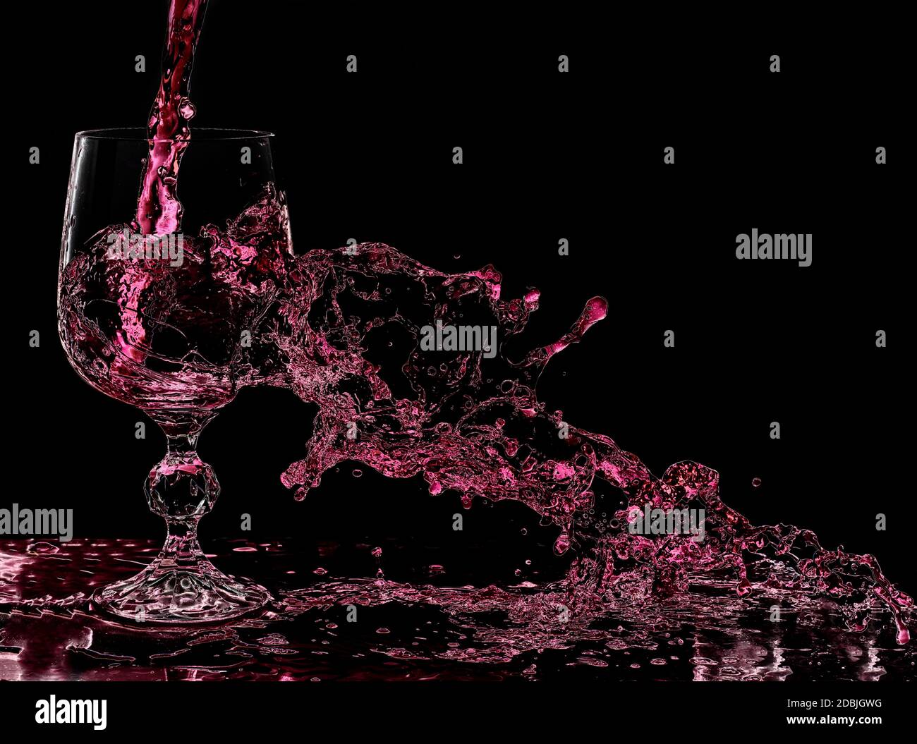 Wine splashes out of glass when poured Stock Photo - Alamy