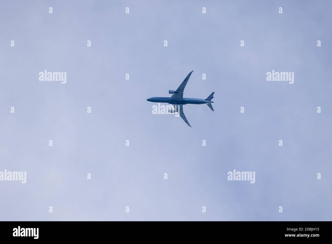 A portrait of a civilian airplane high up in the sky flying by. The ...