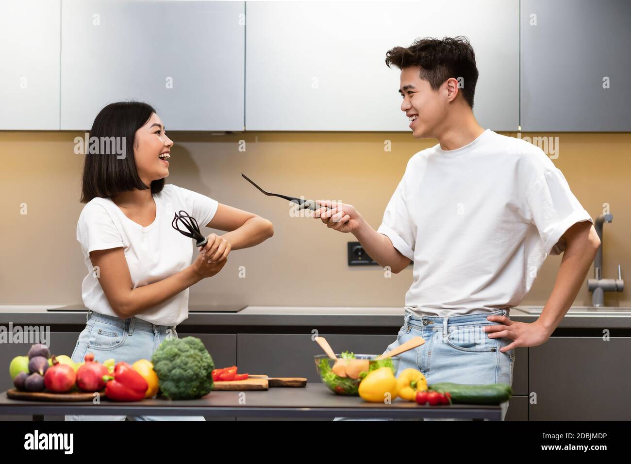 Chinese Couple Having Fun In Kitchen Fencing With Cooking Tools Stock ...