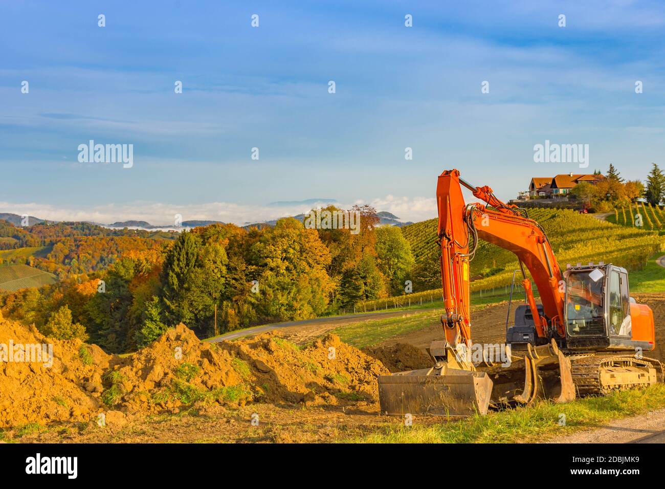 Orange digger/excavator machine excavating the vineyards farmland for ...