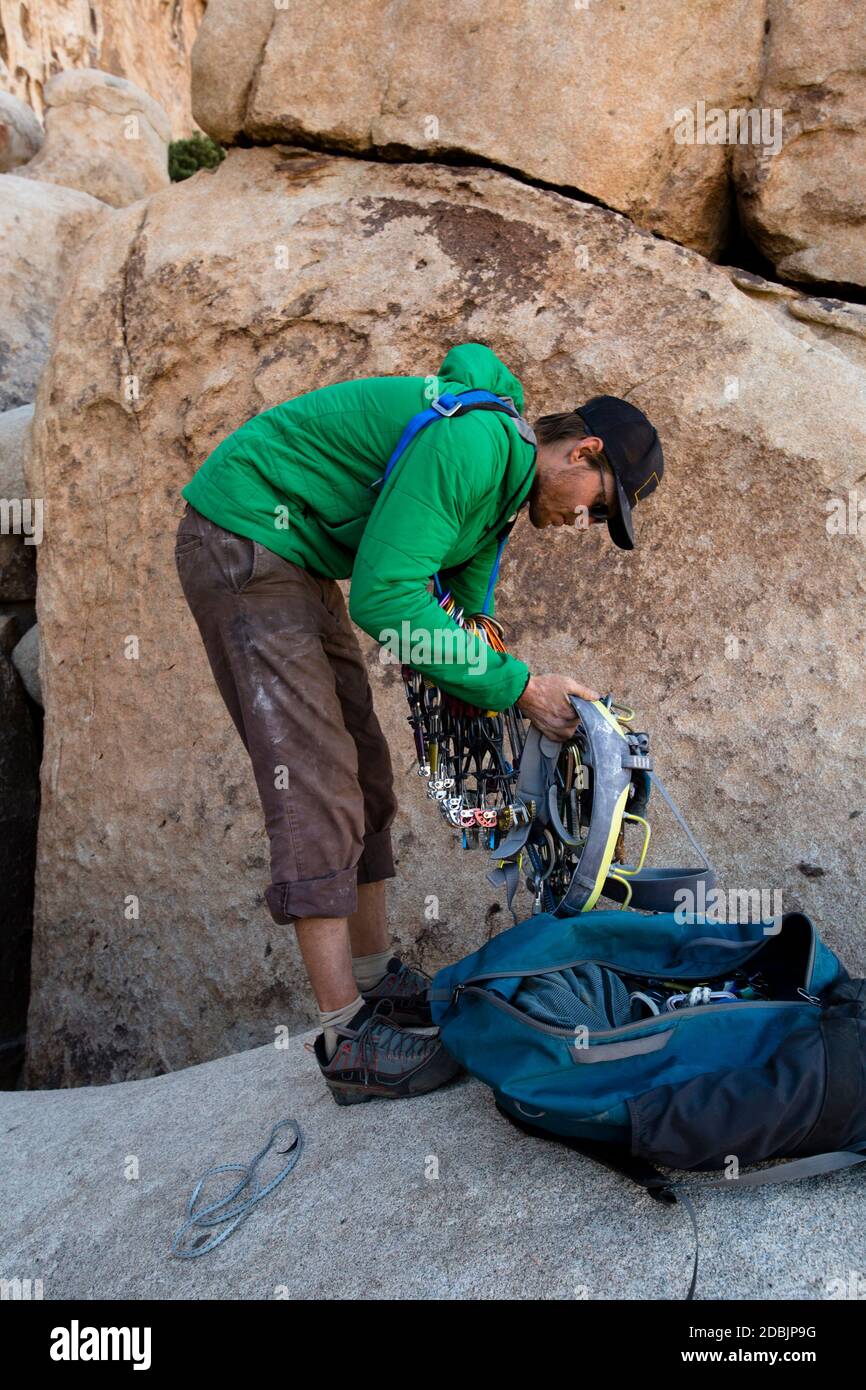 A male climber in a green jacket packs climbing gear in Joshua Tree ...
