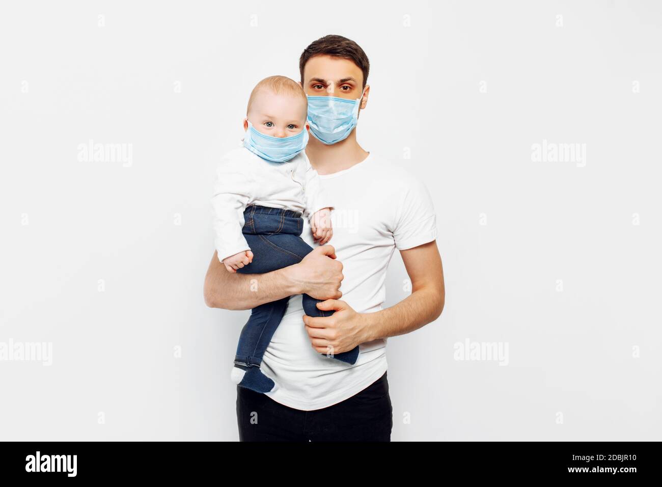 a young father and his young son wear surgical masks to protect against ...