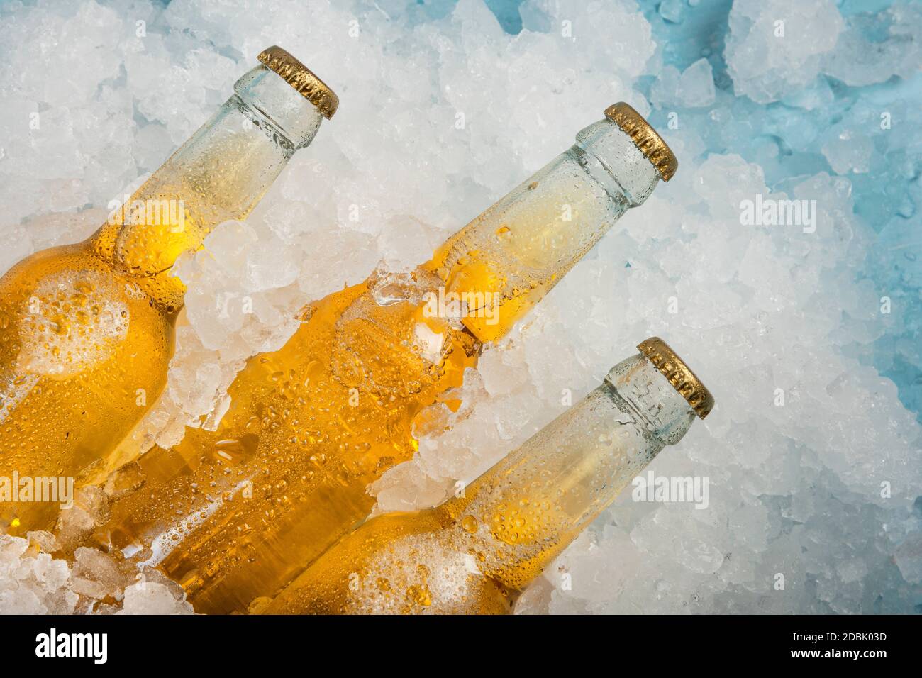 Close up three clear glass bottles of cold lager beer on crushed ice at ...