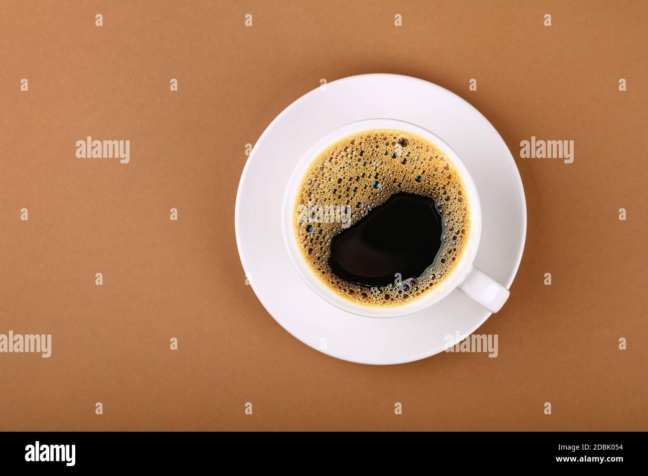 Close up one cup full of black instant frothy coffee on white saucer ...
