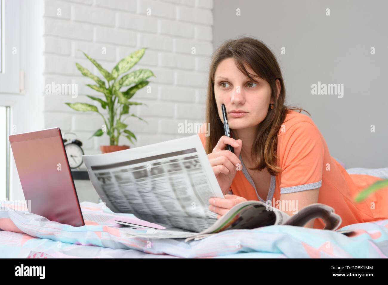 Girl thinking while looking at newspaper job advertisements Stock Photo ...