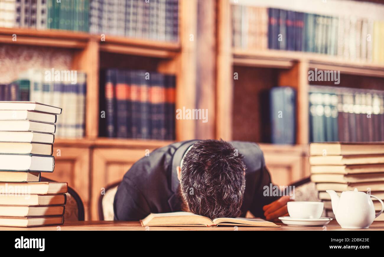 Guy is overworked and sleeps on table. Man sits with head on table with ...