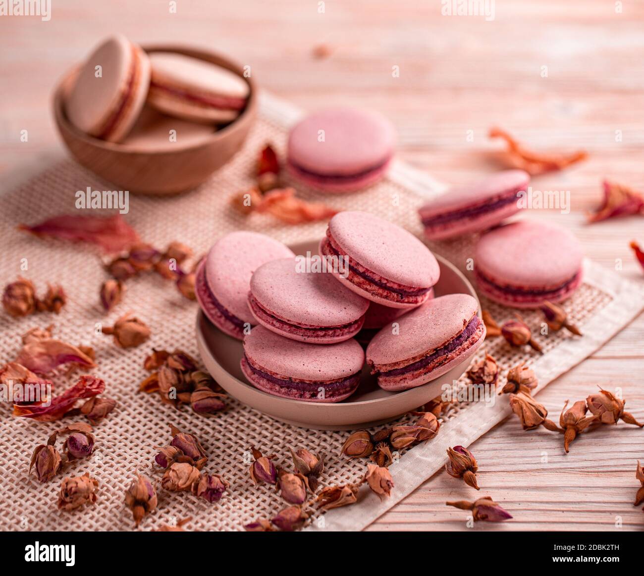 Still life composition of pink macaroons with dried rose buds ...