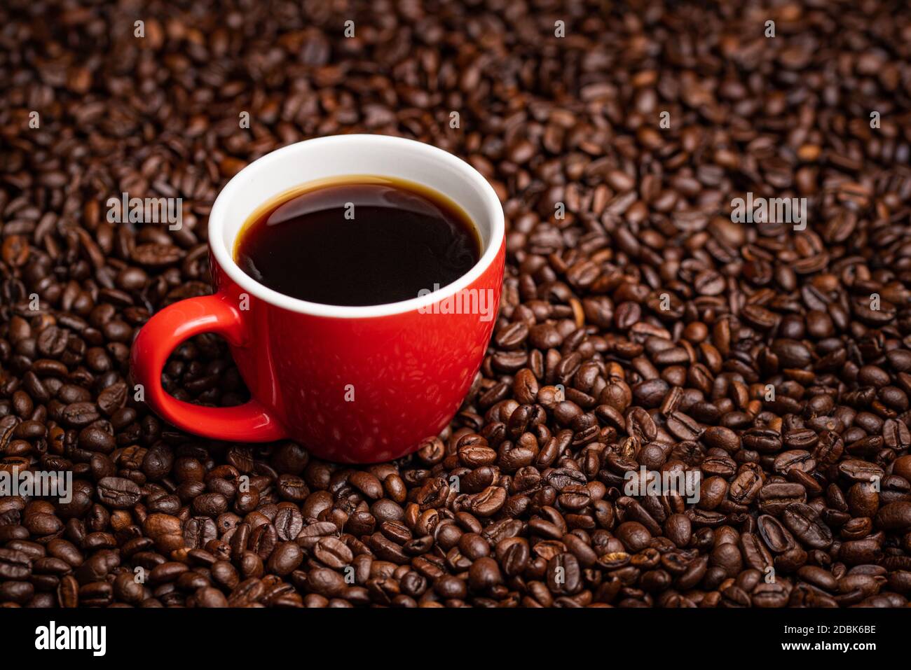 Red Cup of black coffee on table covered with coffee beans. Copy space ...