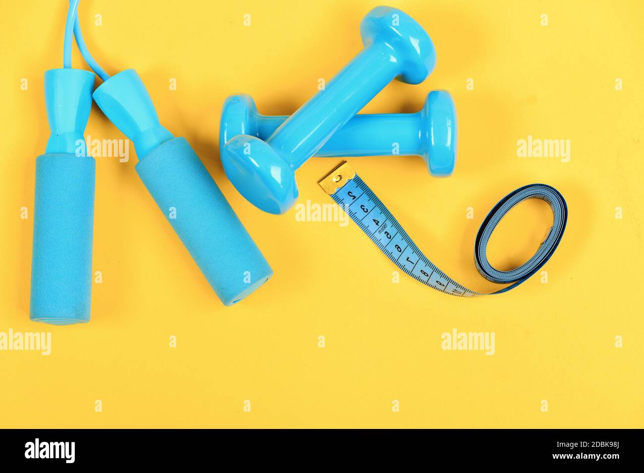 Barbells and skipping rope next to measure tape roll. Sports and ...