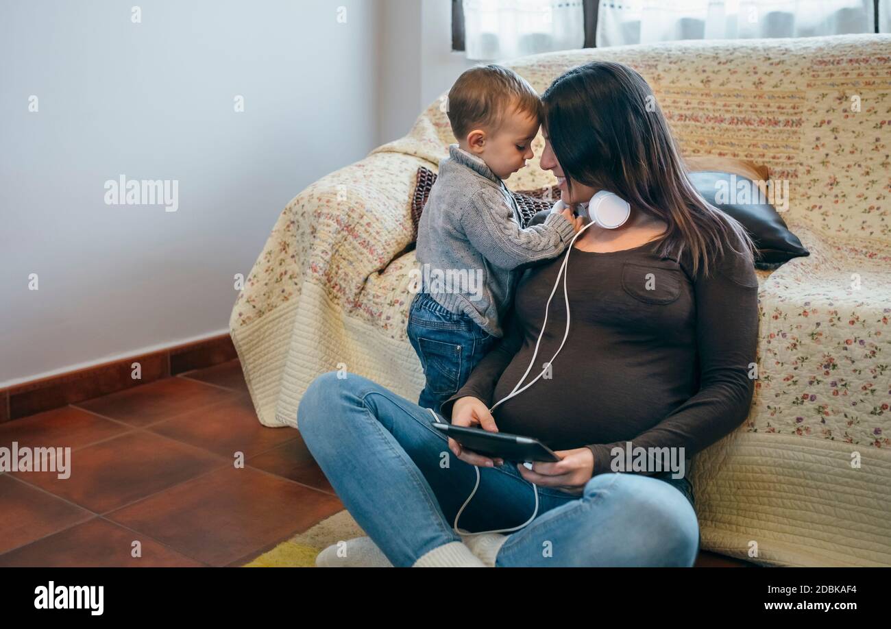 Toddler claiming the attention of his pregnant mother Stock Photo - Alamy