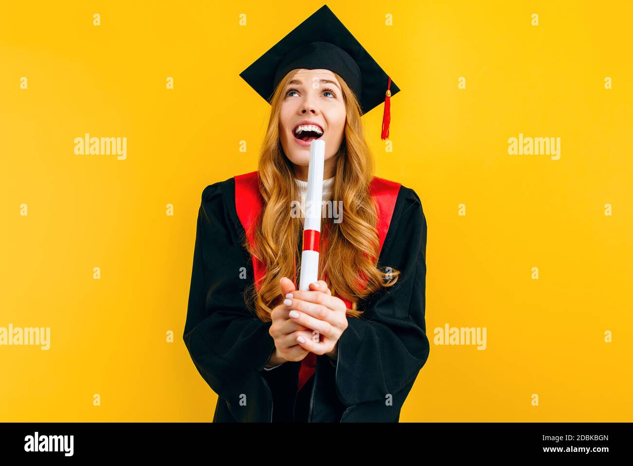 Happy attractive graduate in a master's dress, with a diploma on a ...